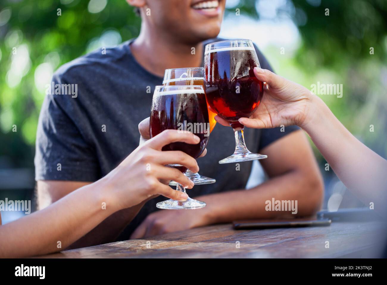Mid section view of three friends toasting with beers Stock Photo - Alamy
