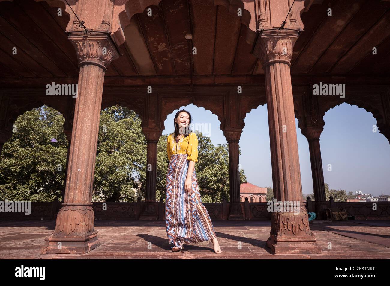 Happy ethnic female in ornamental clothes smiling and looking away ...