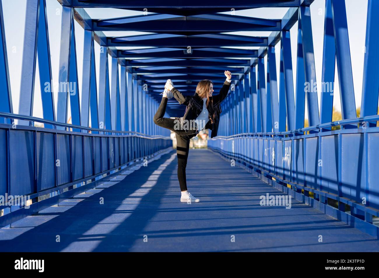 Side view of flexible female dancer performing on bridge while ...