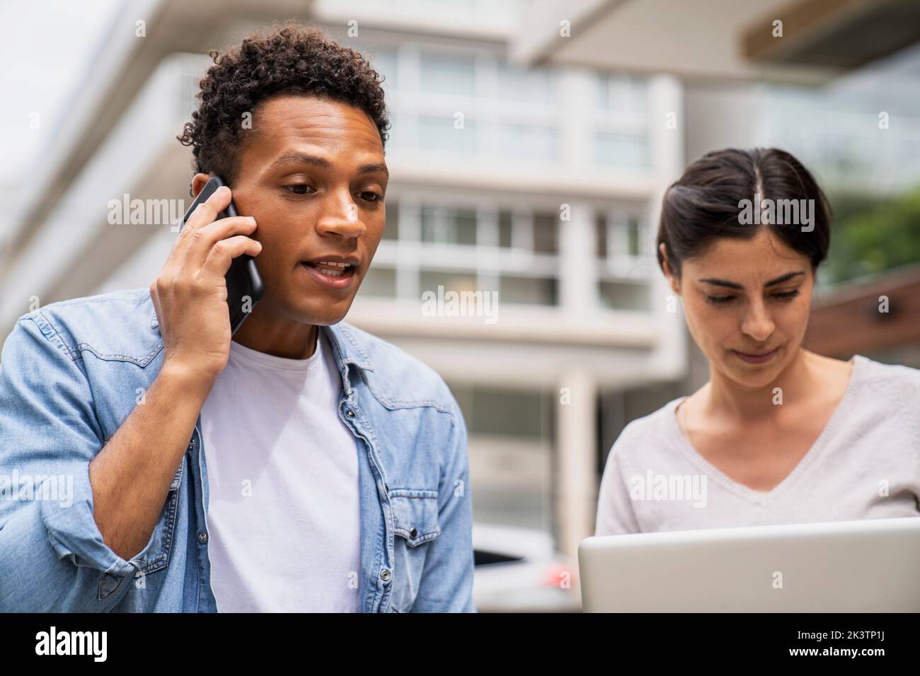 Mid-shot of African-American man speaking on mobile phone and Latin ...