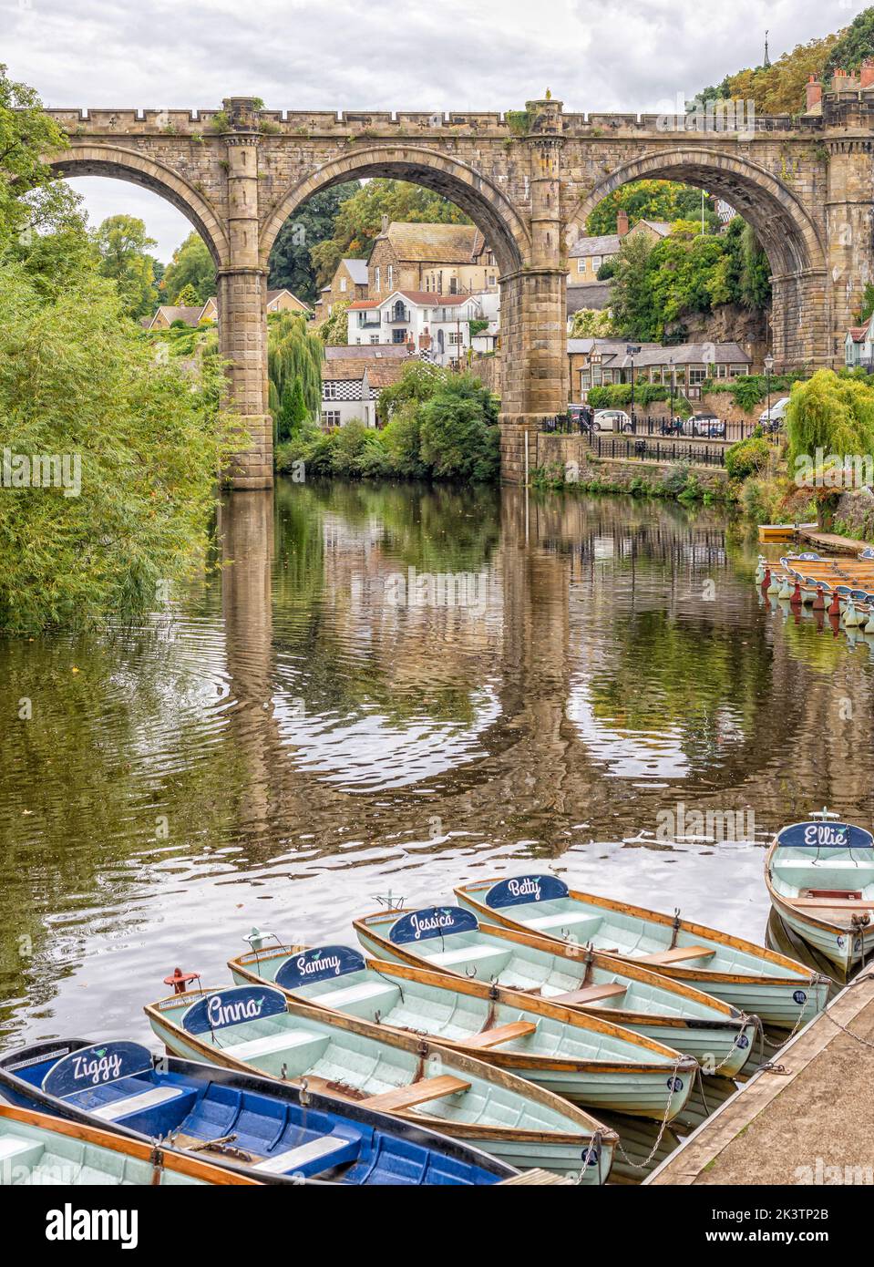 An historic arched viaduct stretches across a river and rowing boats ...