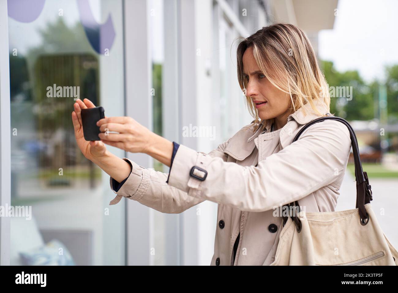 Medium shot of woman taking a photo of shop window with her mobile ...