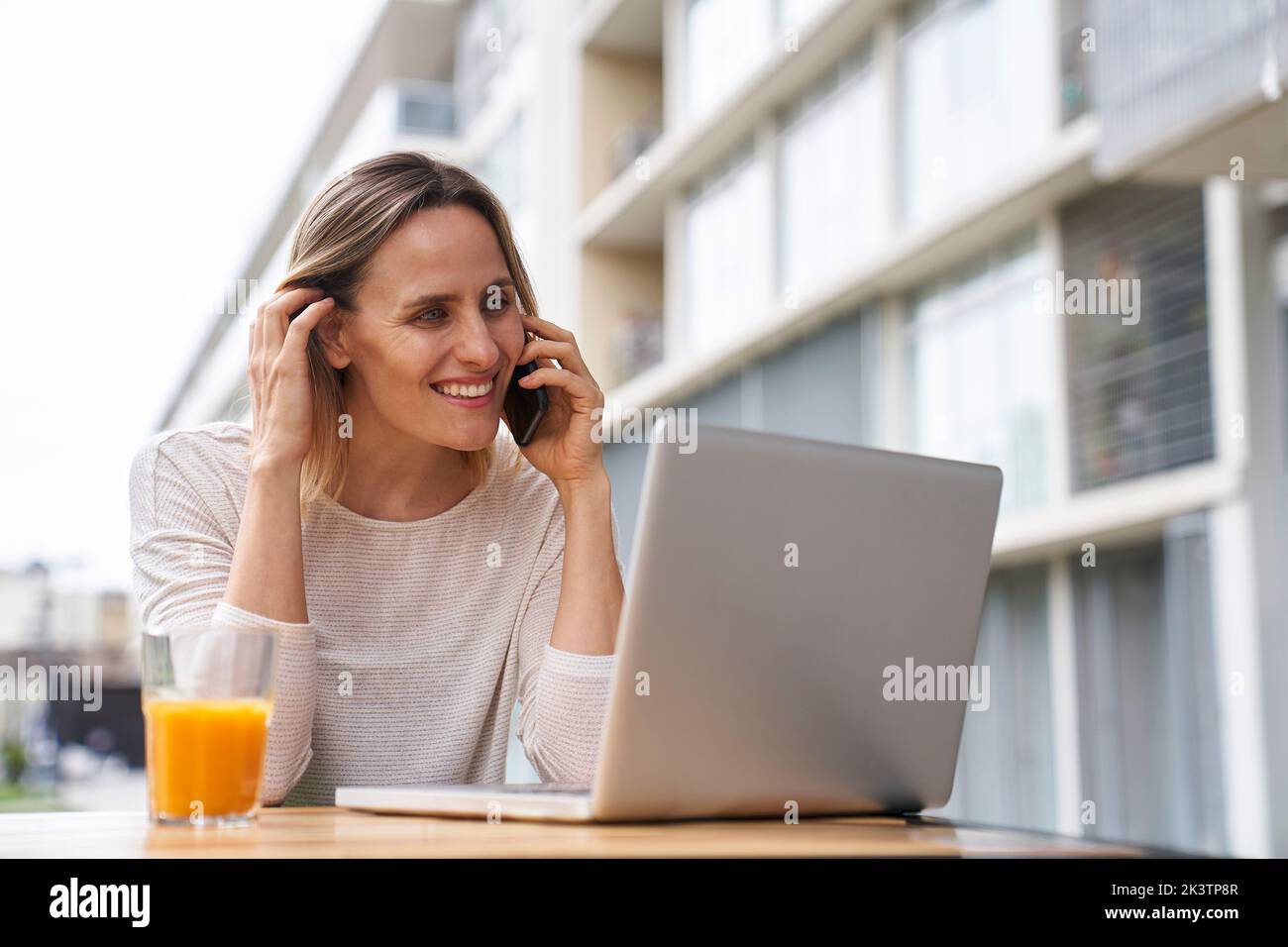 Portrait of smiling attractive woman sitting outdoors looking at laptop ...