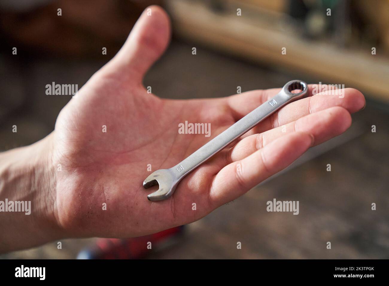 Close-up shot of combination spanner on the palm of a person's hand ...