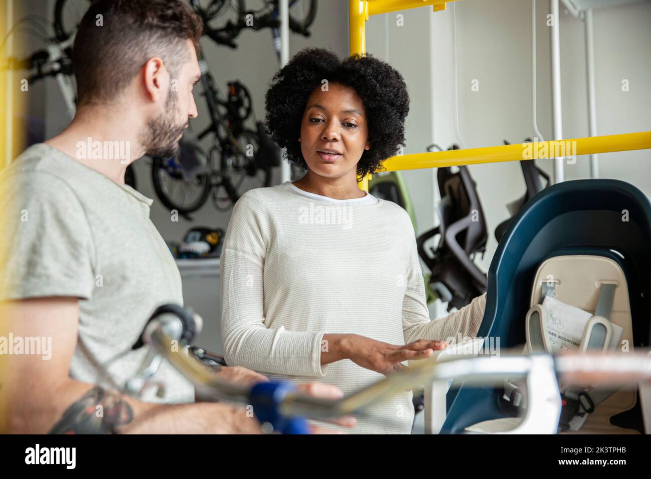 Bicycle store owner talking with African American female customer Stock ...