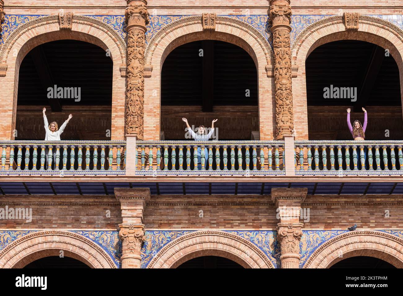 Low angle of carefree females standing with raised arms on arched ...