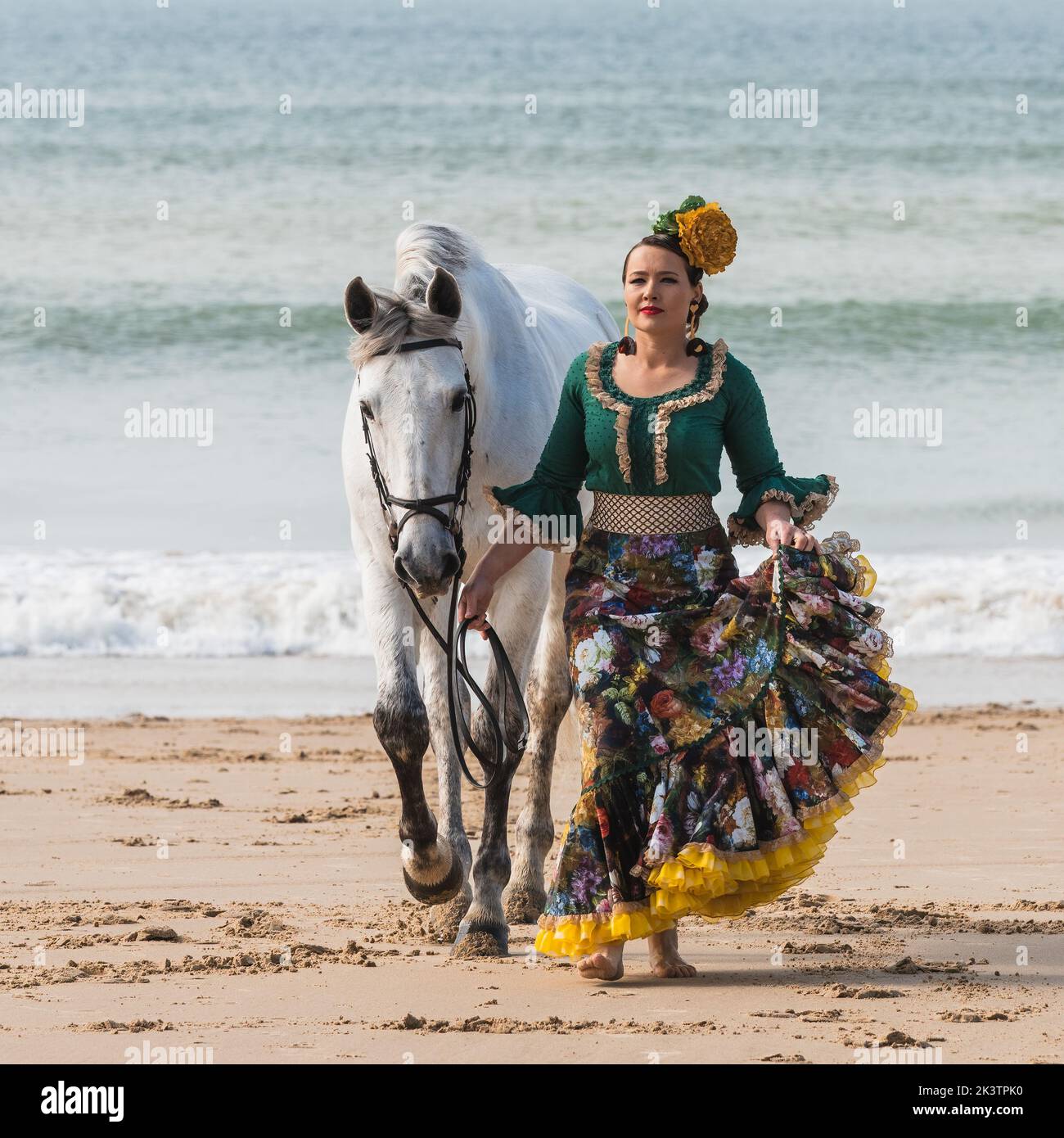Latin female in ruffled traditional flamenco costume walking with gray ...