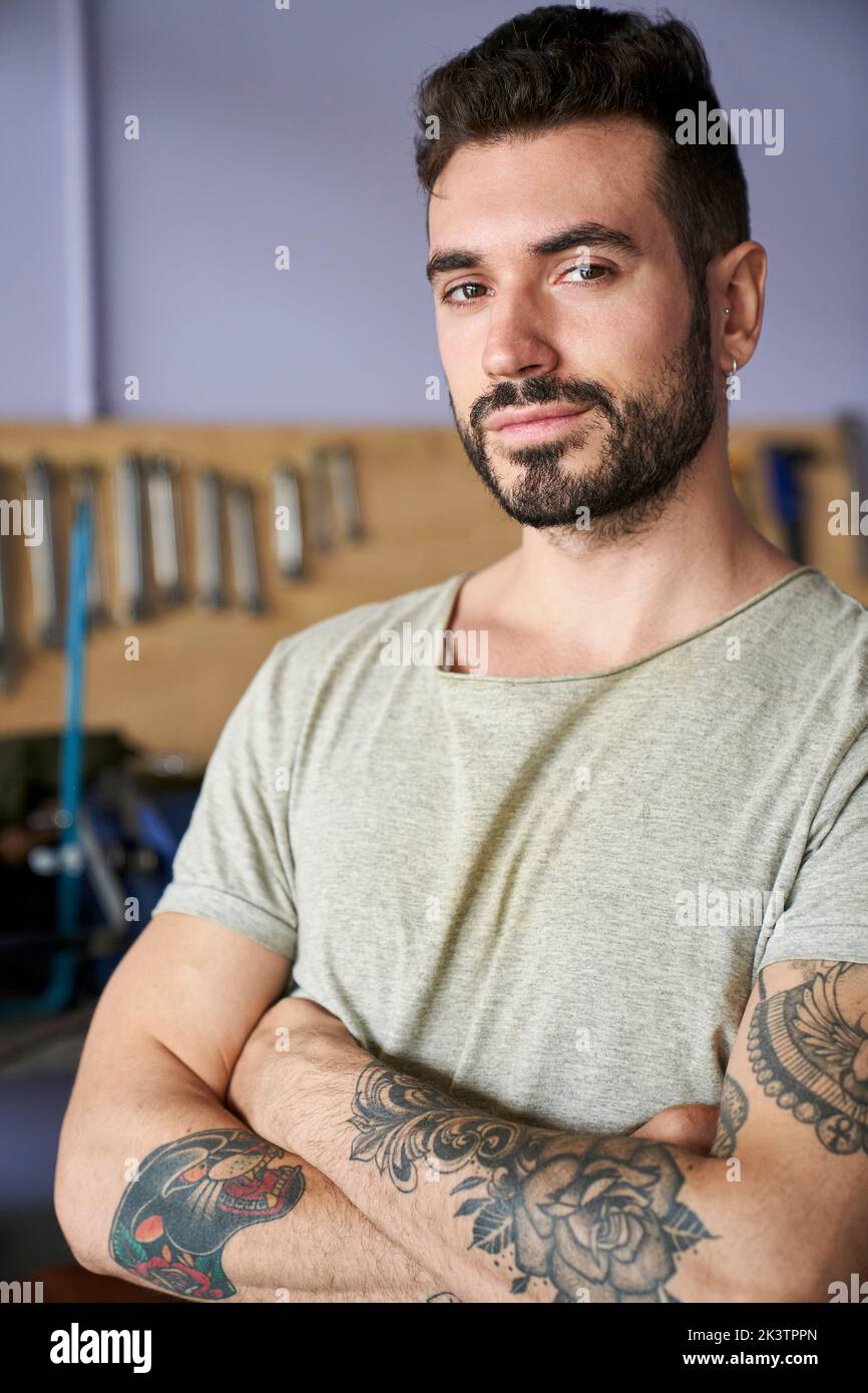 Medium-shot portrait of bearded shop owner standing in his workshop in ...