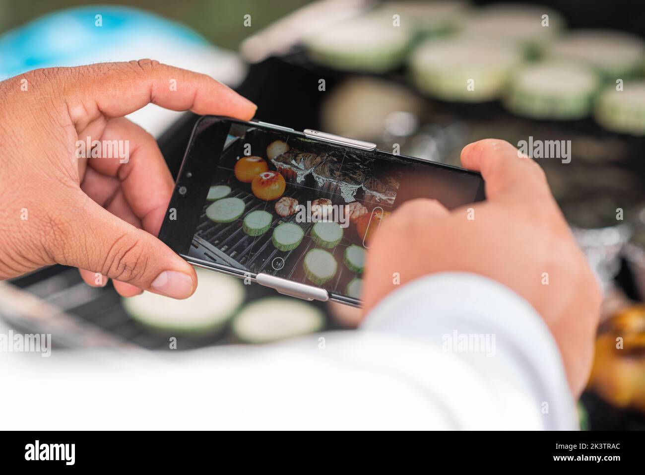 Crop anonymous man taking photo on mobile phone of grate of grill with ...