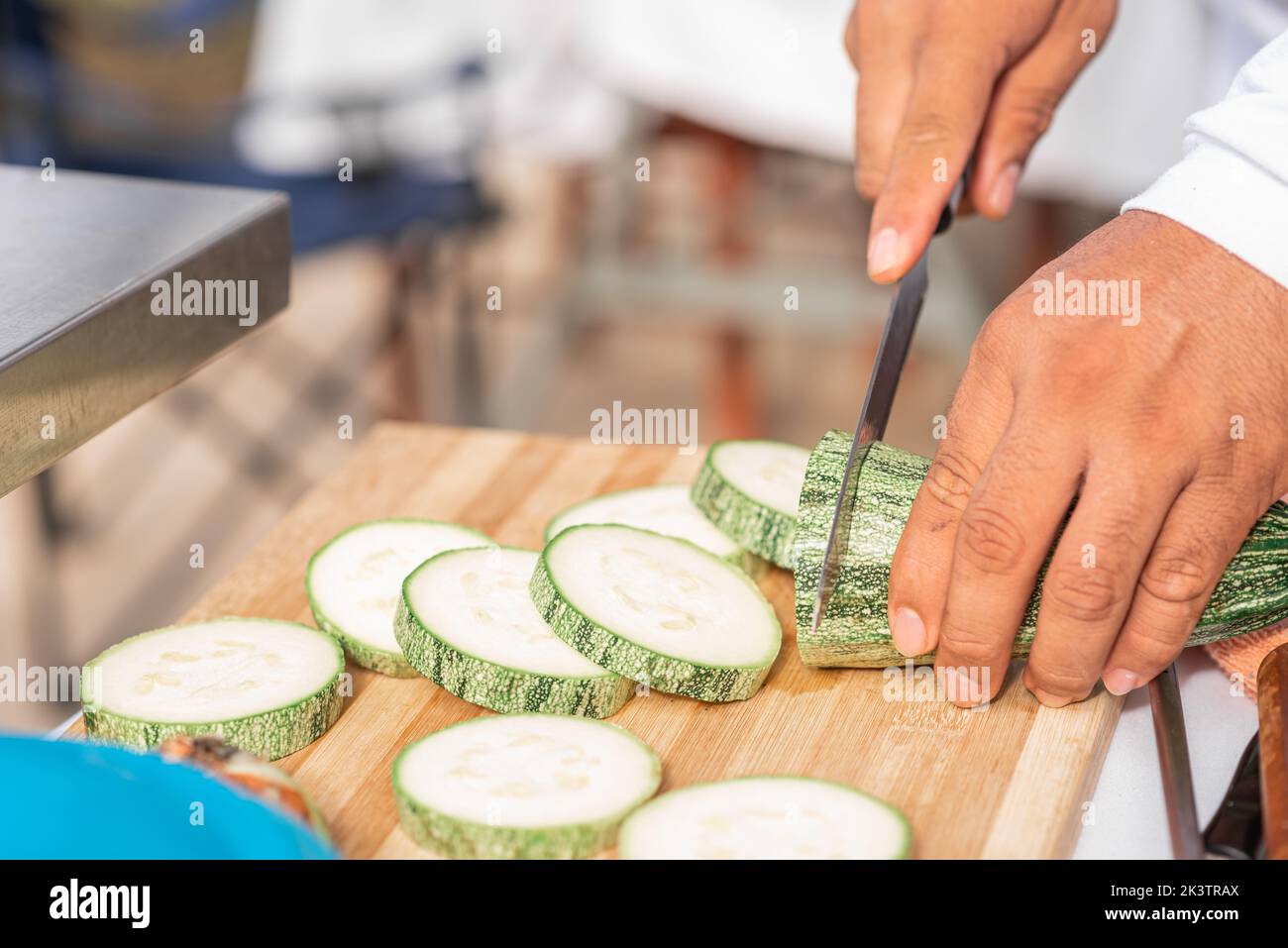 Crop anonymous male chef slicing fresh ripe zucchini with knife on ...