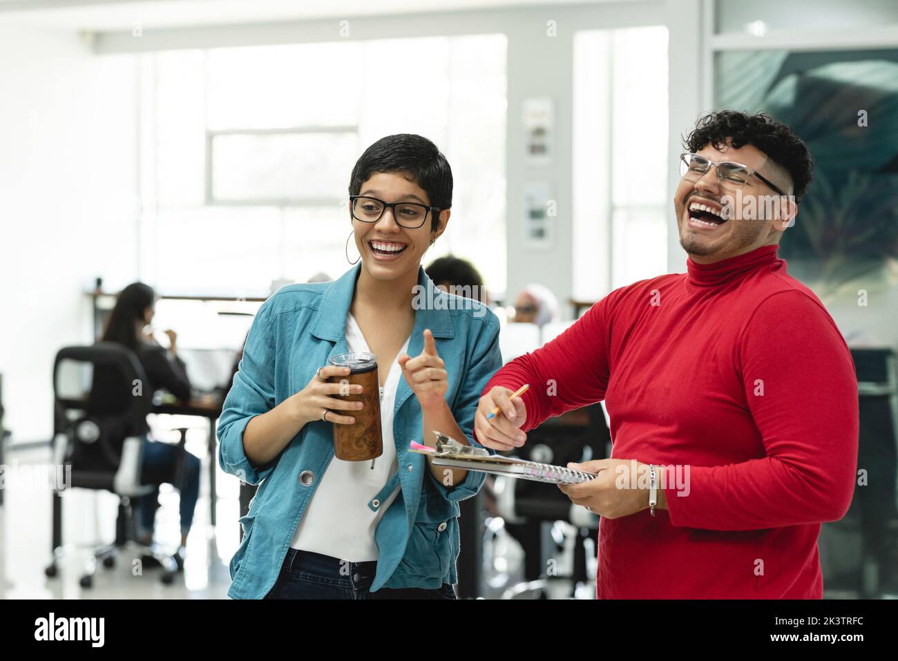 Happy Hispanic female with thermo mug standing near cheerful coworker ...
