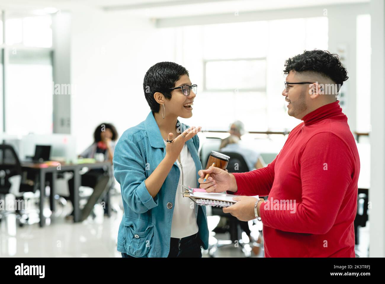 Happy Hispanic female with thermo mug standing near cheerful coworker ...