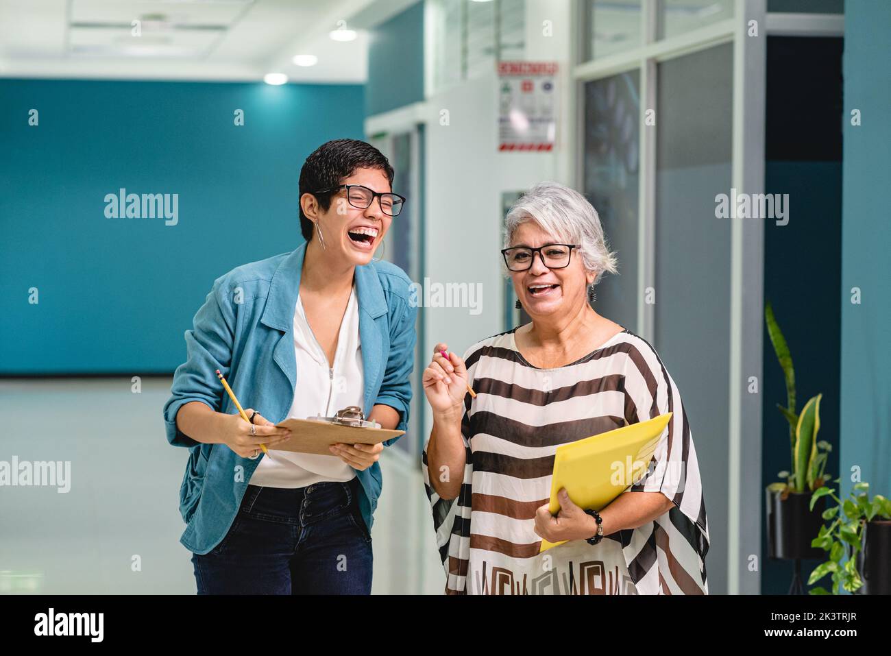 Happy Hispanic women coworkers in trendy clothes standing and taking ...