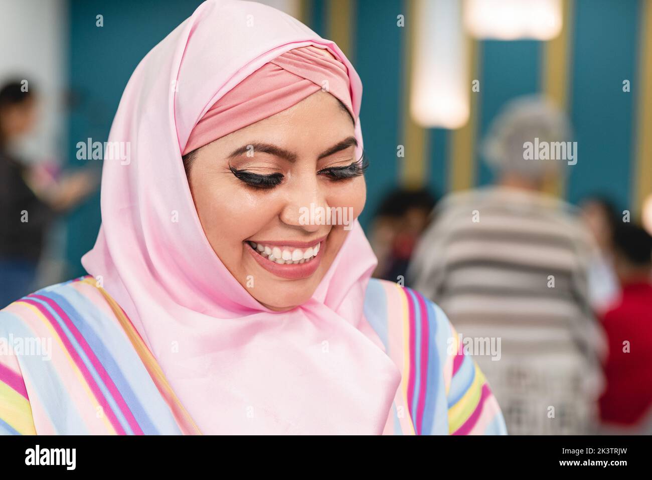 Positive Muslim woman in pink hijab and colorful dress standing in ...