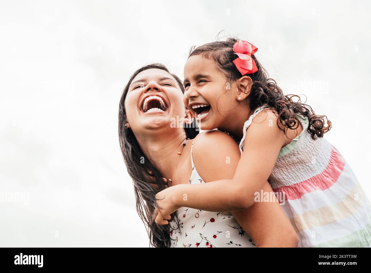 Happy Hispanic woman giving piggyback ride to cute girl while spending ...