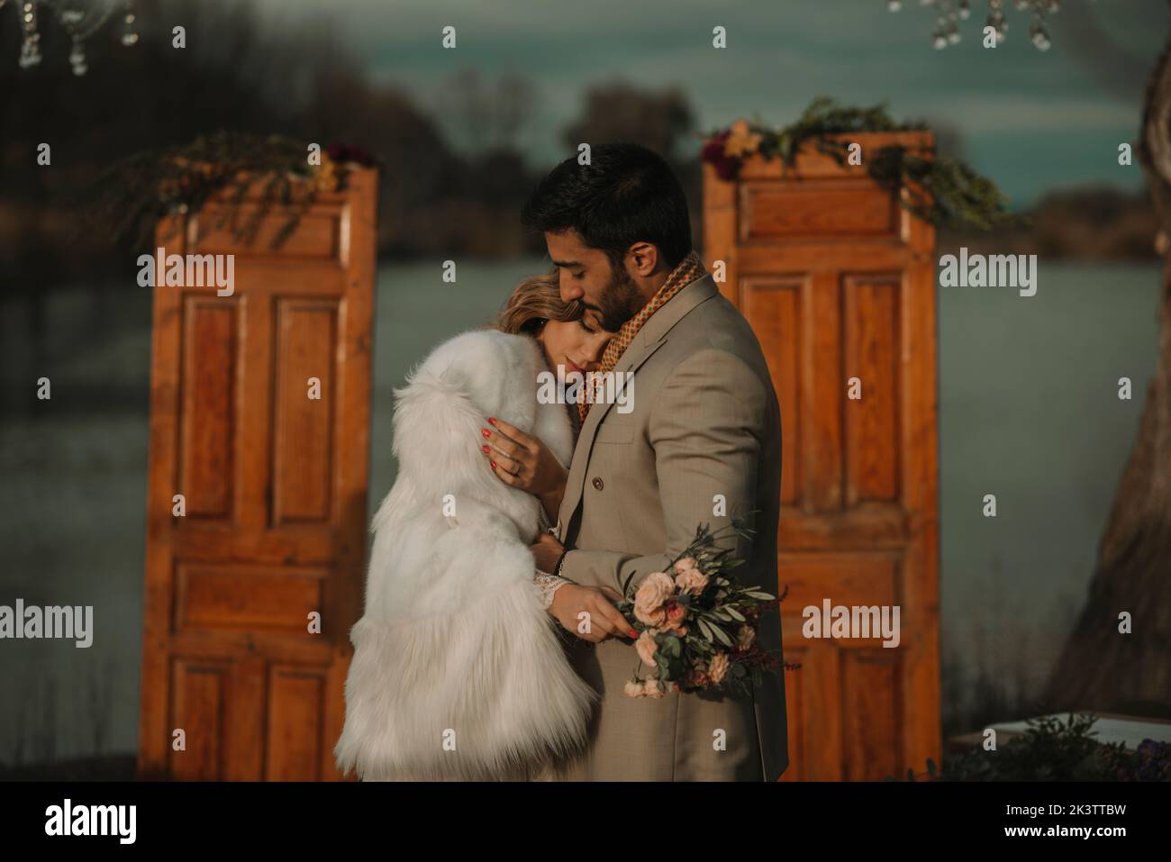 Side view of young guy in grey costume hugging and kissing attractive ...