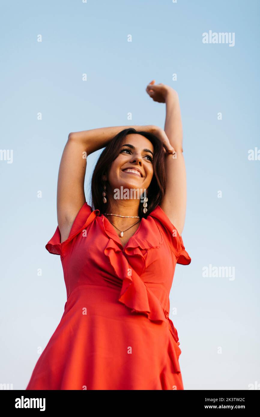 From below of smiling female wearing pendant and earrings looking away ...