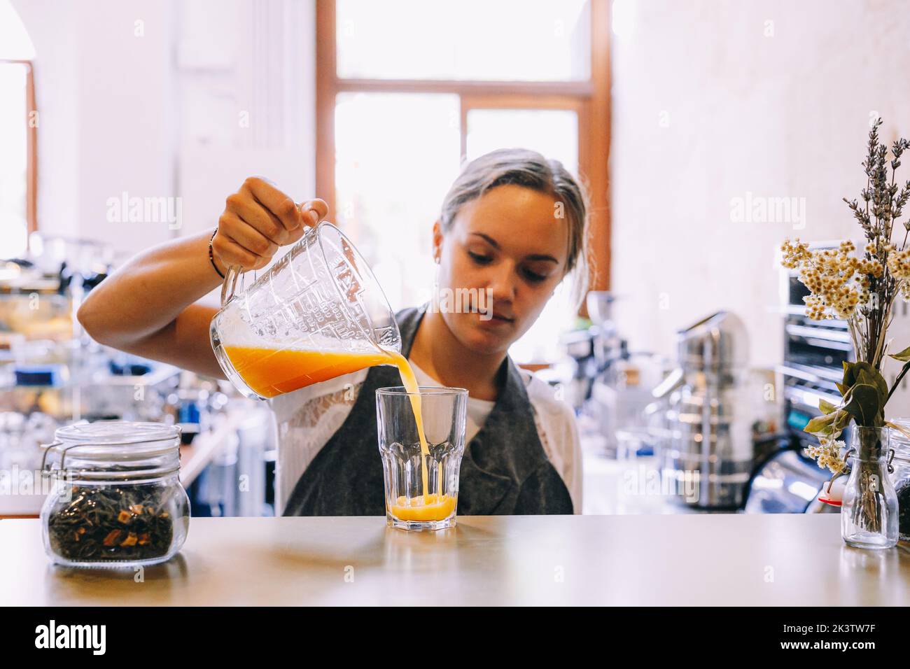 diligent barista preparing citrus fresh juice in shiny juicer at table ...