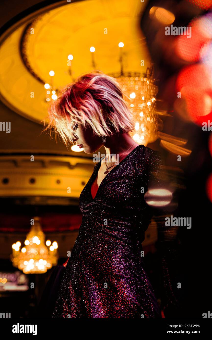 Low angle side view of female in stylish dress dancing in illuminated ...