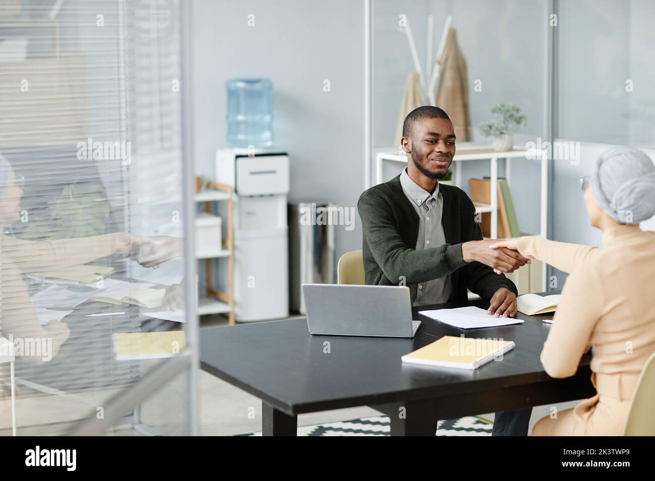 Wide angle of young black man shaking hands with female HR manager ...