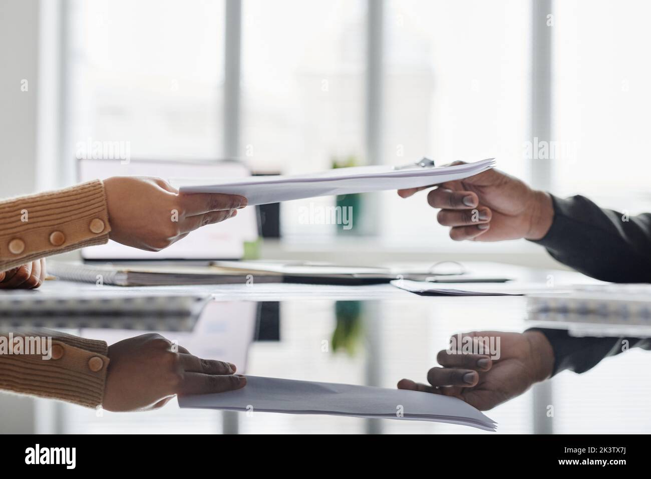 Side view of two hands handing document or contract over meeting table ...
