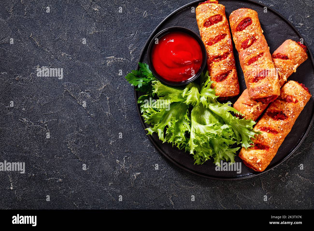 chorizo and semi-dried tomato puff pastry rolls on black plate with ...