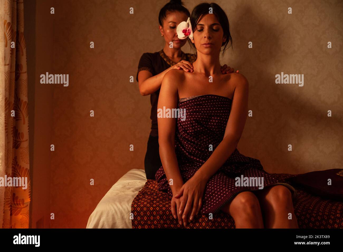 Asian female massagist in traditional clothes giving a thai massage to ...