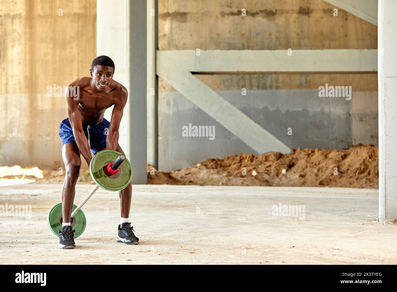 Athletic black young man lifting a heavy-weight barbell in outdoor gym ...