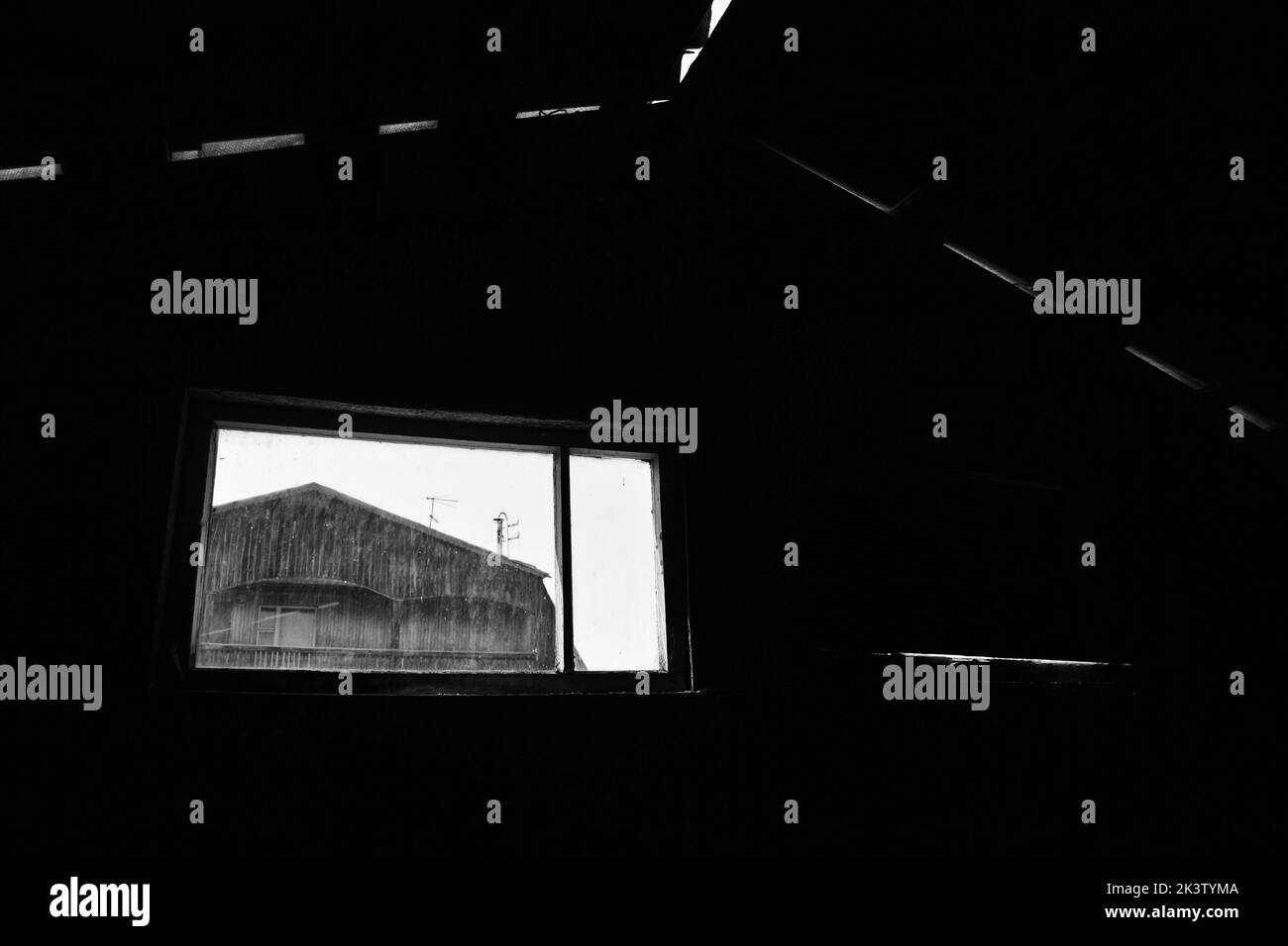 A grayscale shot of an old house seen through a window from the dark ...