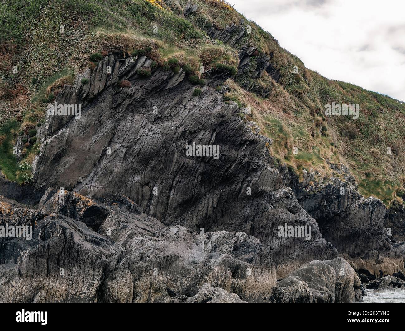 A stone hill covered with grass. Sheer rock. Landscape. Green grass on ...