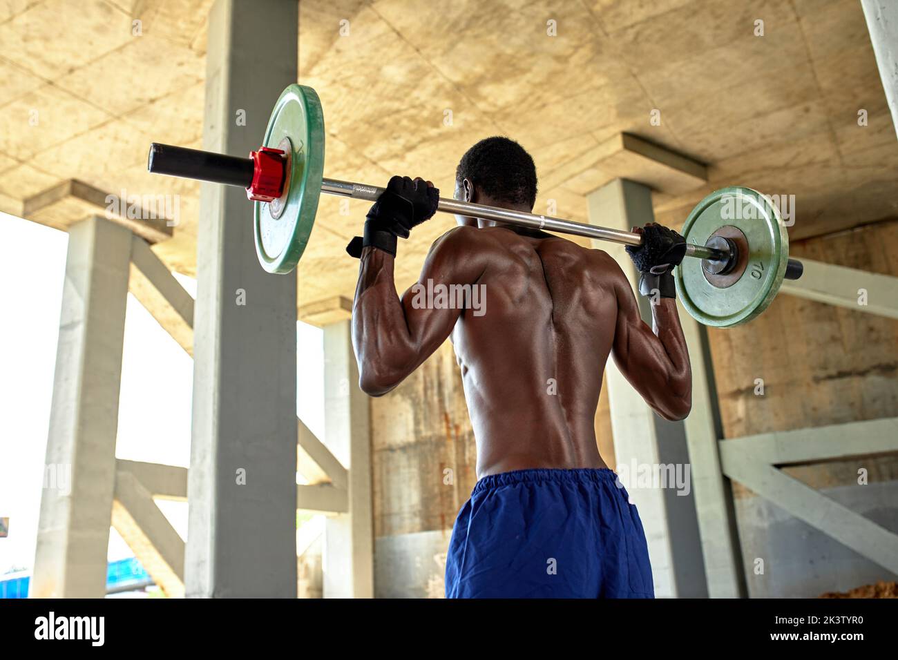 Athletic black young man lifting a heavy-weight barbell in outdoor gym ...