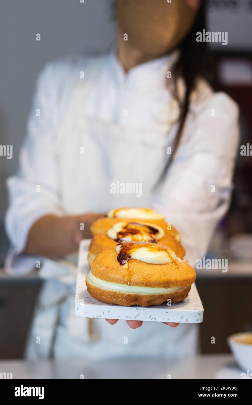 Anonymous crop baker standing with sweet vegan Berliners with sugar ...