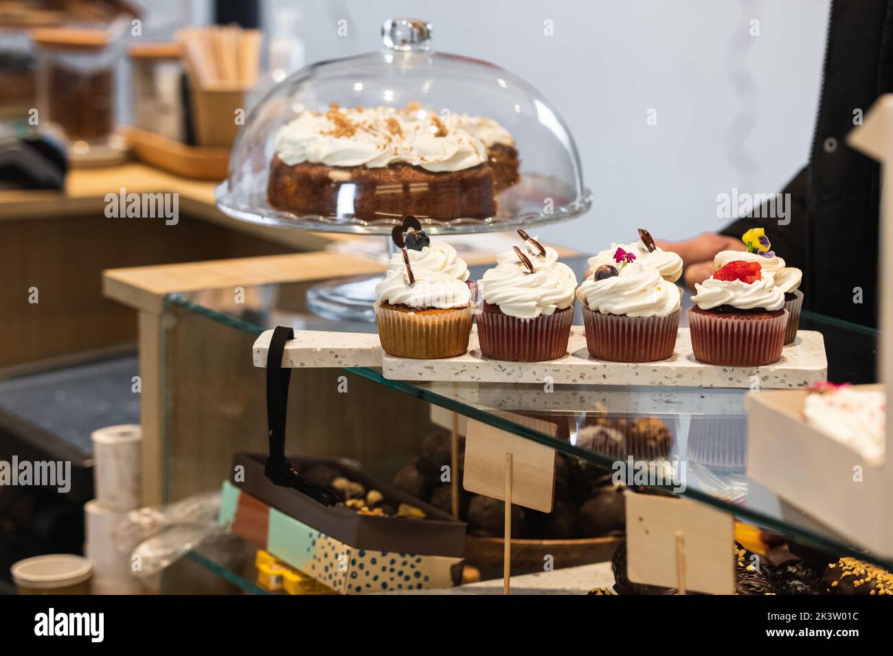 Assorted sweet vegan cupcakes on cutting board placed on glass stall in ...