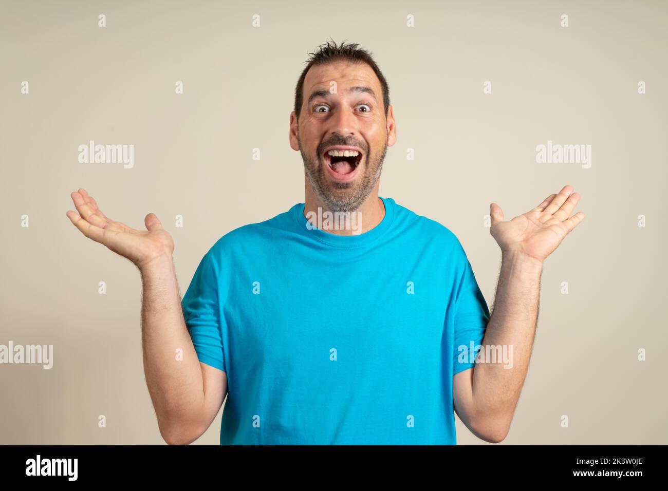 Funny smiling man in blue t-shirt showing palms up, unexpected surprise ...