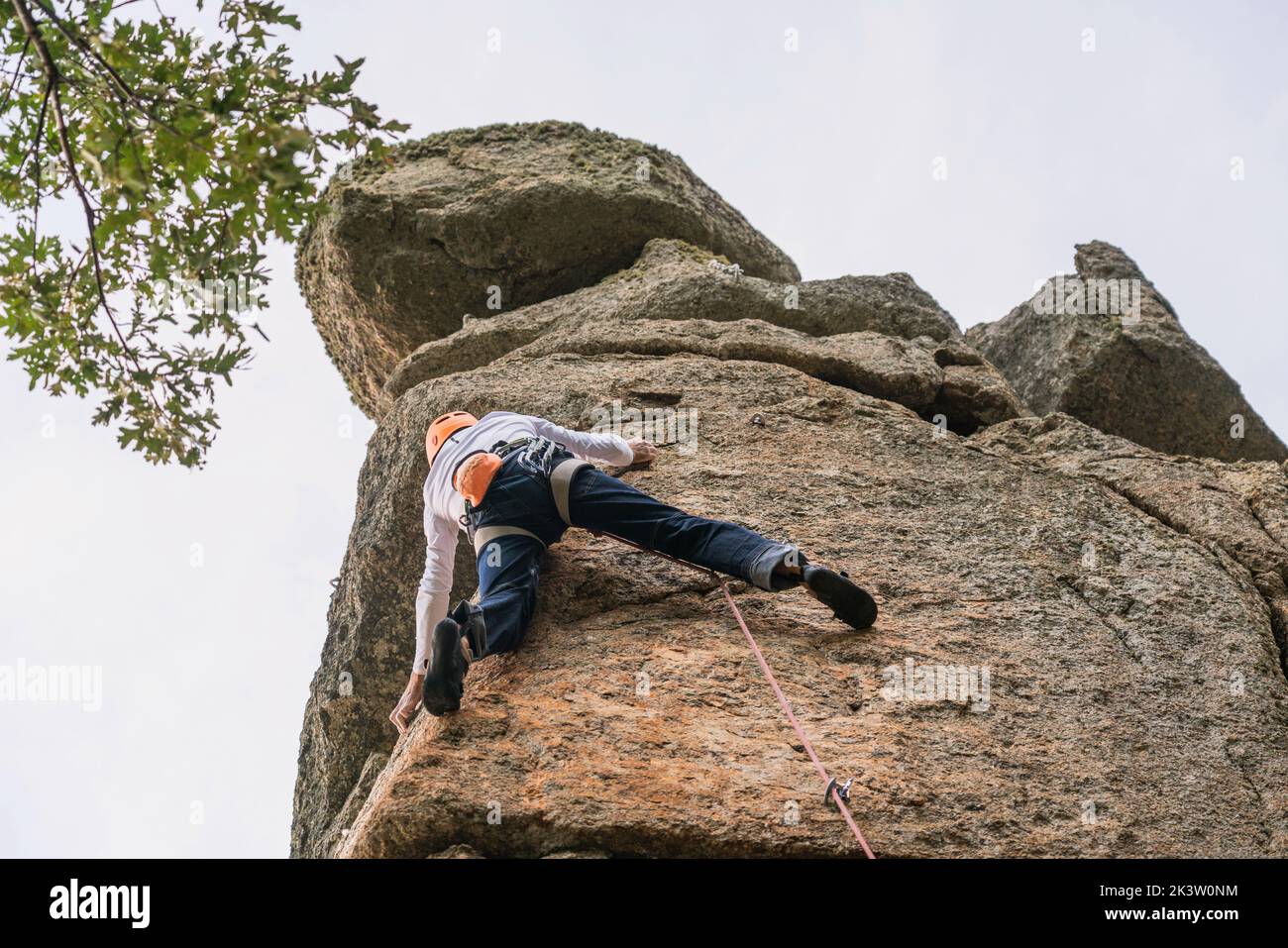 Male mountaineer climbing high cliff with safety carabiner and ropes ...