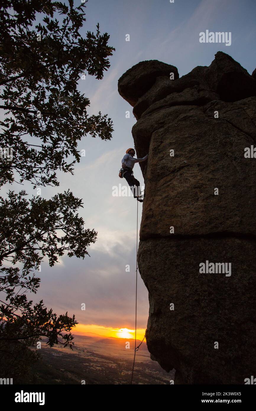 Side view of active climber in protective helmet hanging on mountain ...