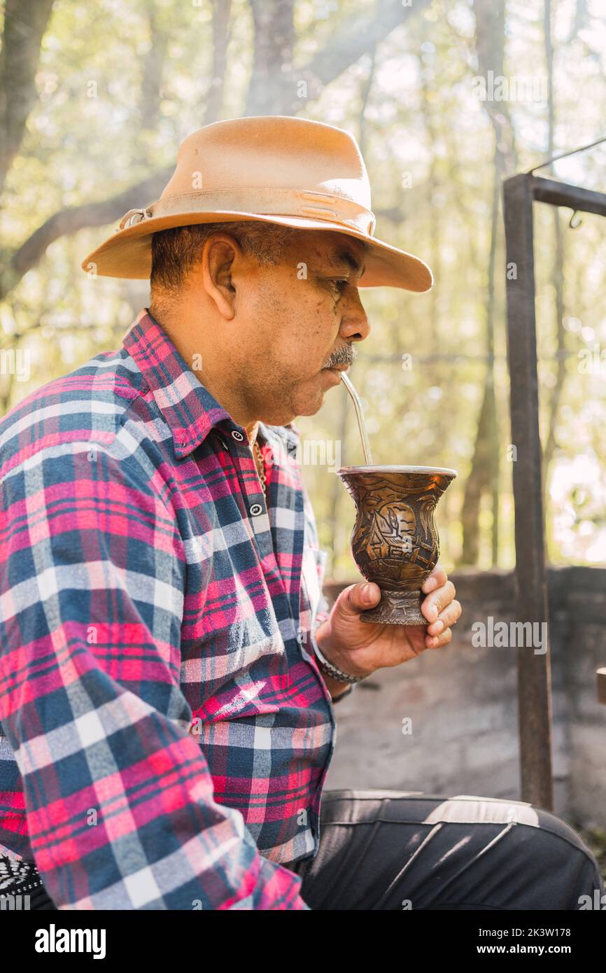 Side view of Argentinian male drinking mate from calabash gourd near ...