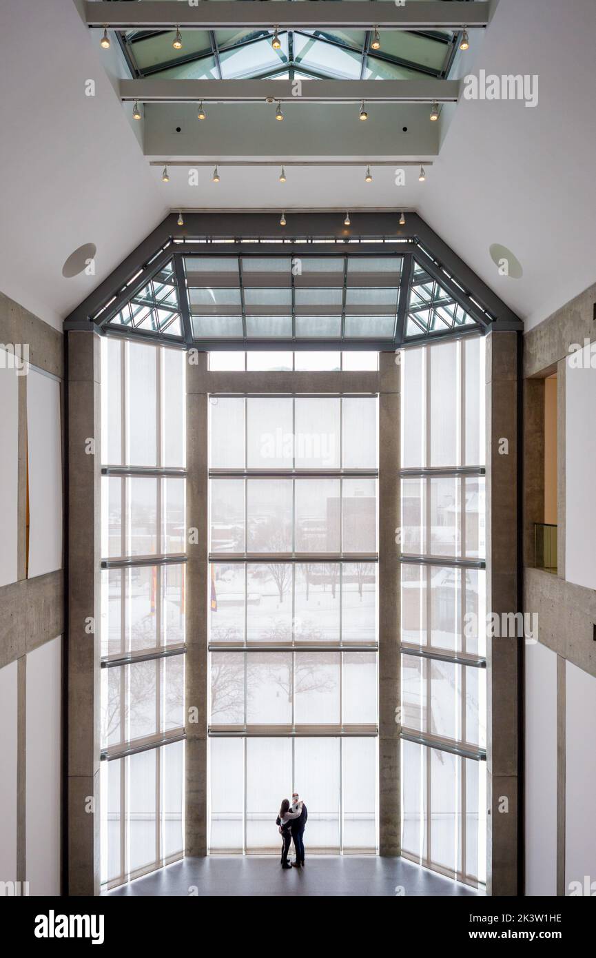 Couple, lovers facing a large window inside a large glass room in the ...