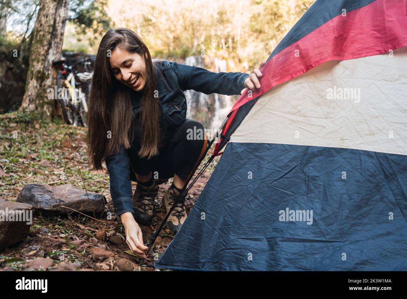 Full body of positive young female hiker sitting on haunches while ...
