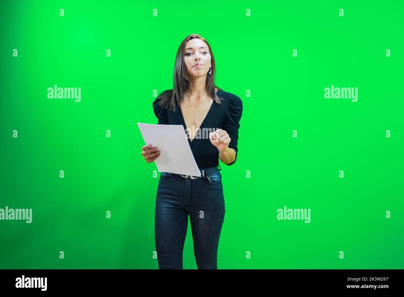 Female host with paper wearing decollete blouse and jeans standing on ...