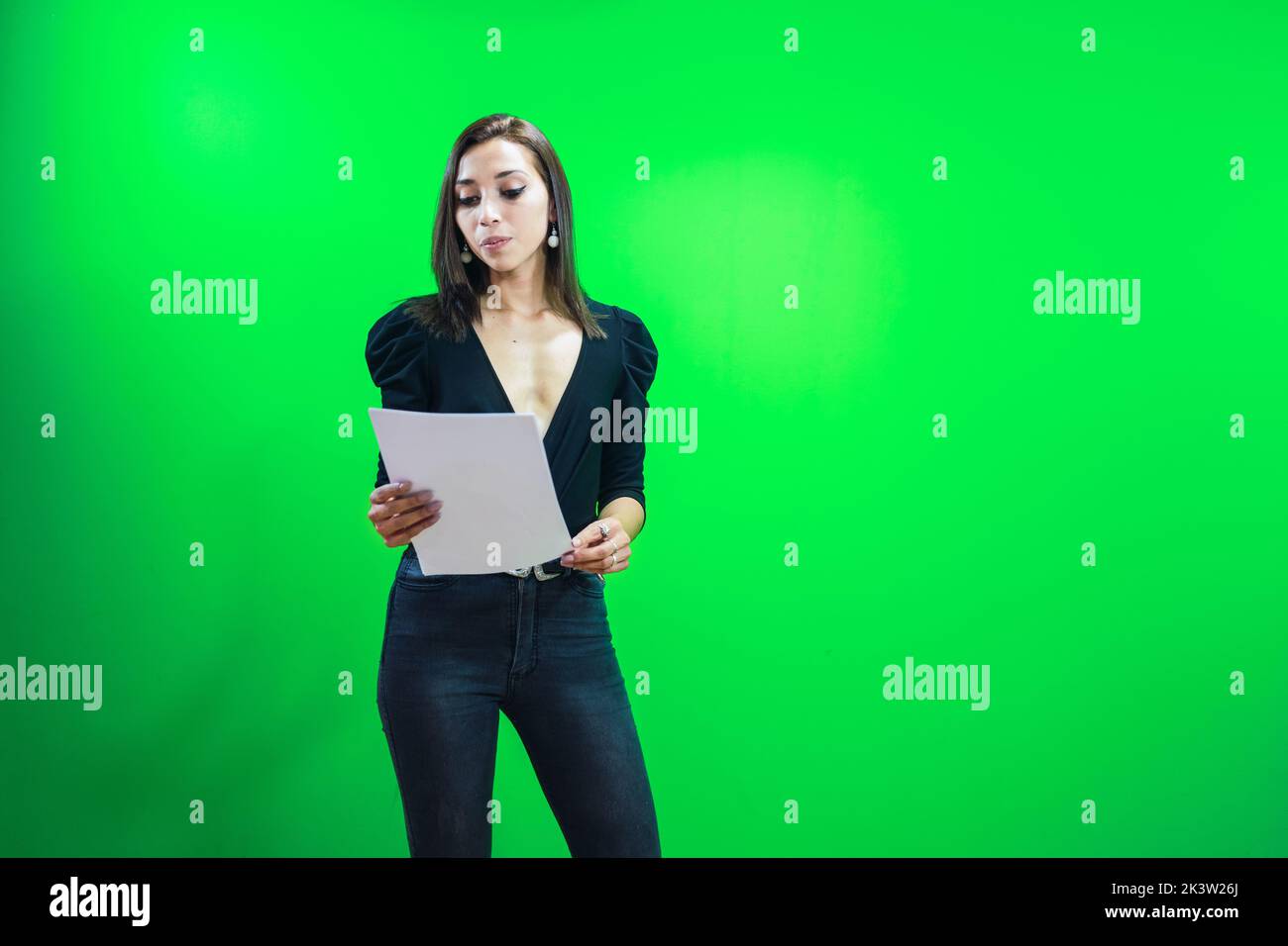 Female host with paper wearing decollete blouse and jeans standing on ...