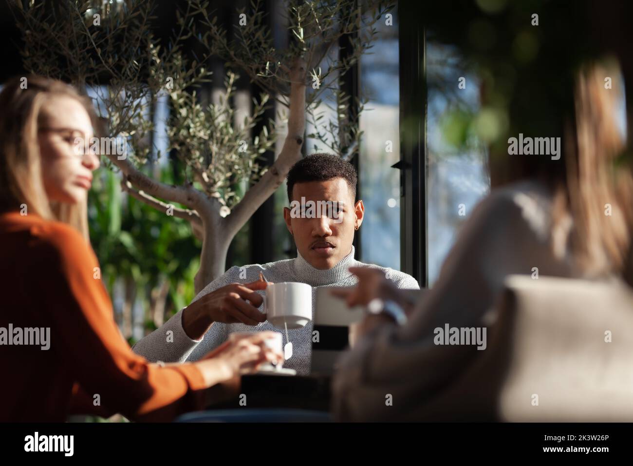 Three friends in a restaurant talking smiling and drinking tea ...