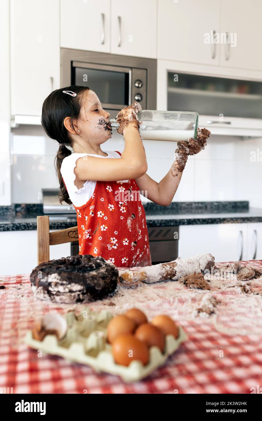 Dirty child drinking milk from bottle against table with tasty ...