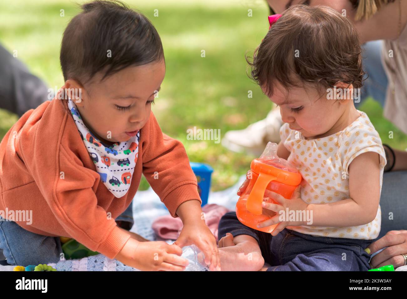 Cute little girl and boy playing with feeding bottle with water while ...