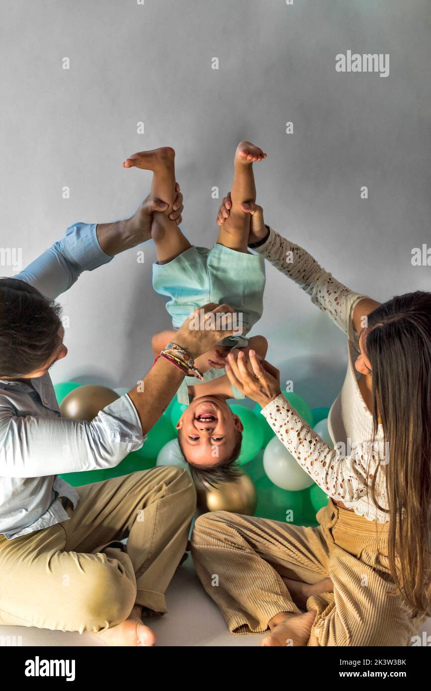 Parents playing with small baby while holding legs and tickling in ...