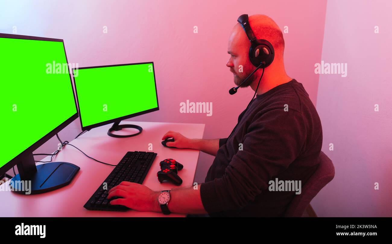 Bald bearded man wearing headset is sitting and playing at the computer ...