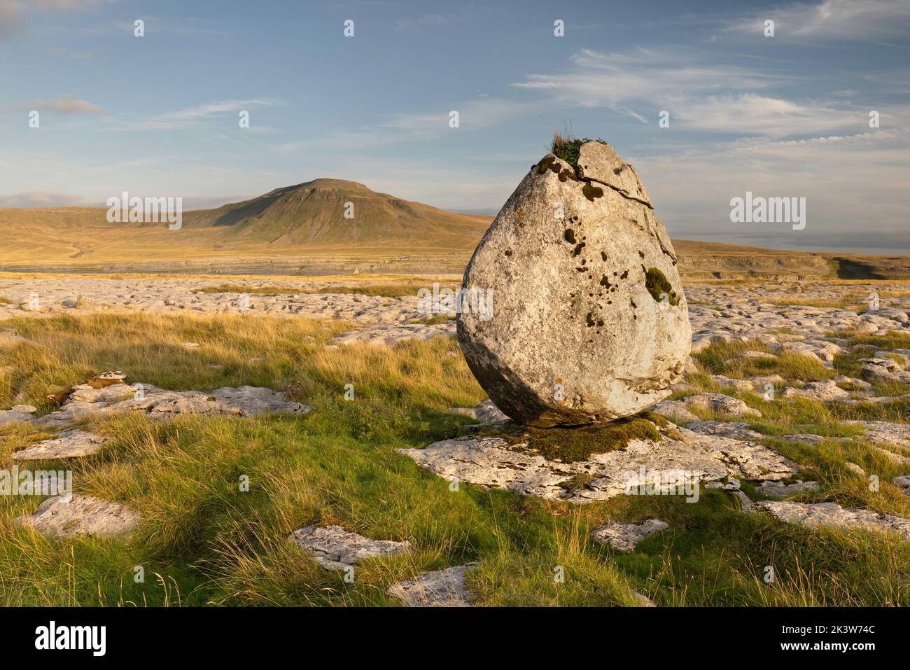 A large boulder stands on limestone pavement in the Yorkshire Dales, in ...