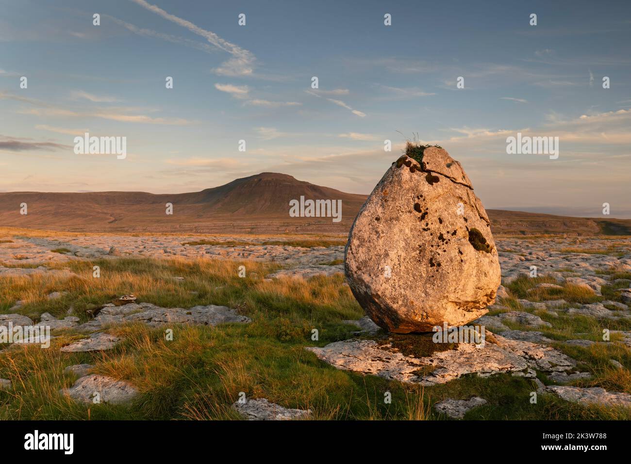 A large boulder stands on limestone pavement in the Yorkshire Dales, in ...