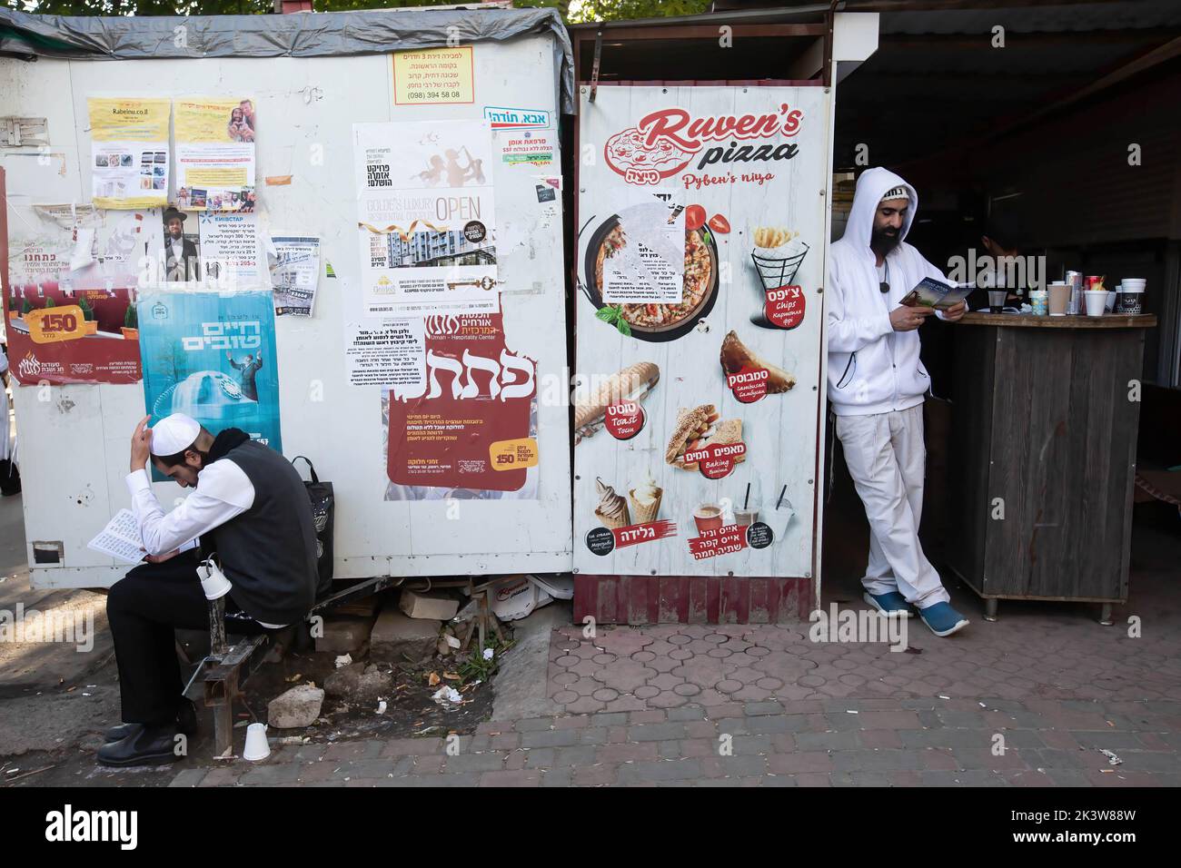 Ultra-Orthodox Jewish pilgrims pray next to a fast food restaurant ...