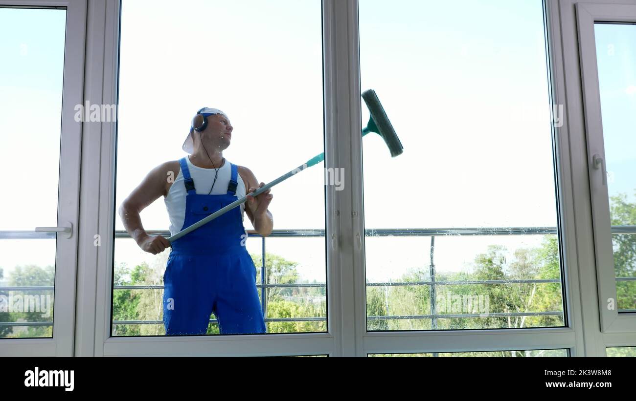 view through window,handsome male worker of cleaning service, in blue ...